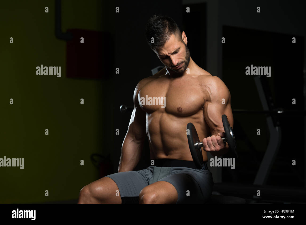Healthy Man Working Out Biceps In A Dark Gym - Dumbbell Concentration ...