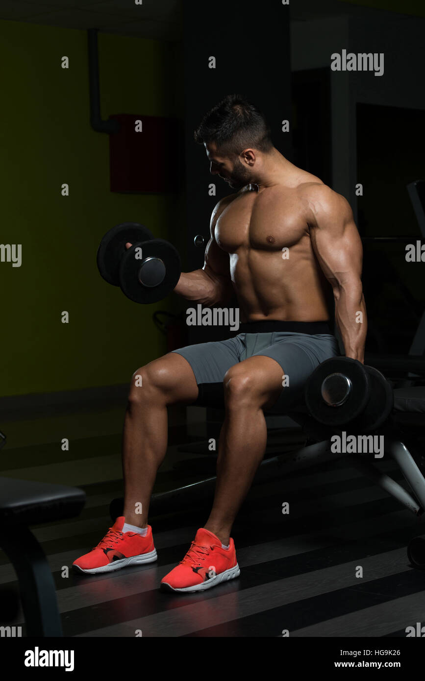 Healthy Man Working Out Biceps In A Dark Gym - Dumbbell Concentration ...