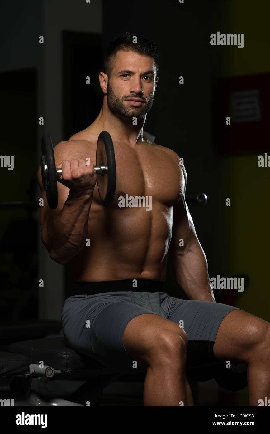 Healthy Man Working Out Biceps In A Dark Gym - Dumbbell Concentration ...