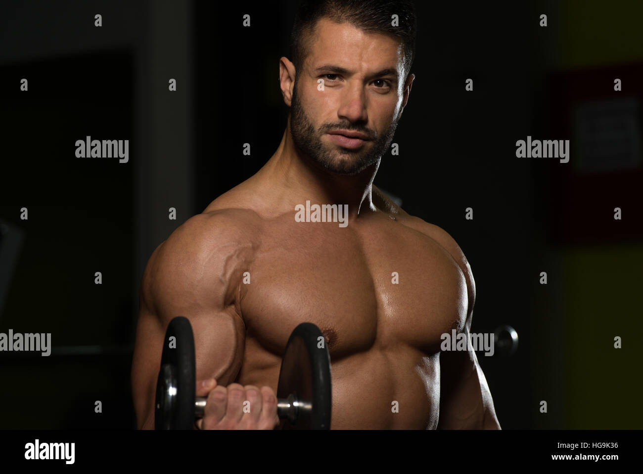 Healthy Man Working Out Biceps In A Dark Gym - Dumbbell Concentration ...