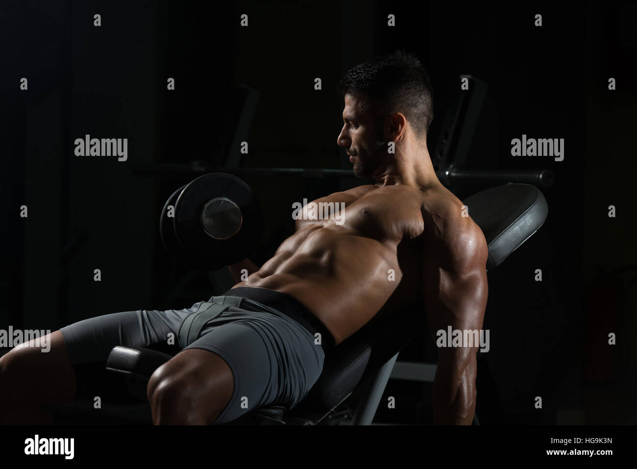 Healthy Man Working Out Biceps In A Dark Gym - Dumbbell Concentration ...