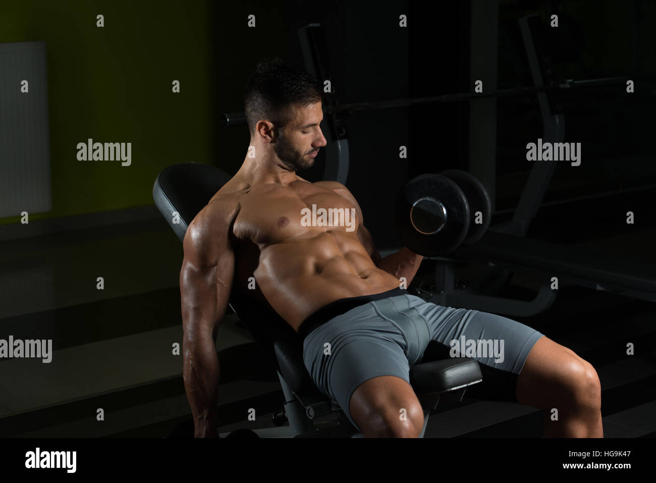 Healthy Man Working Out Biceps In A Dark Gym - Dumbbell Concentration ...