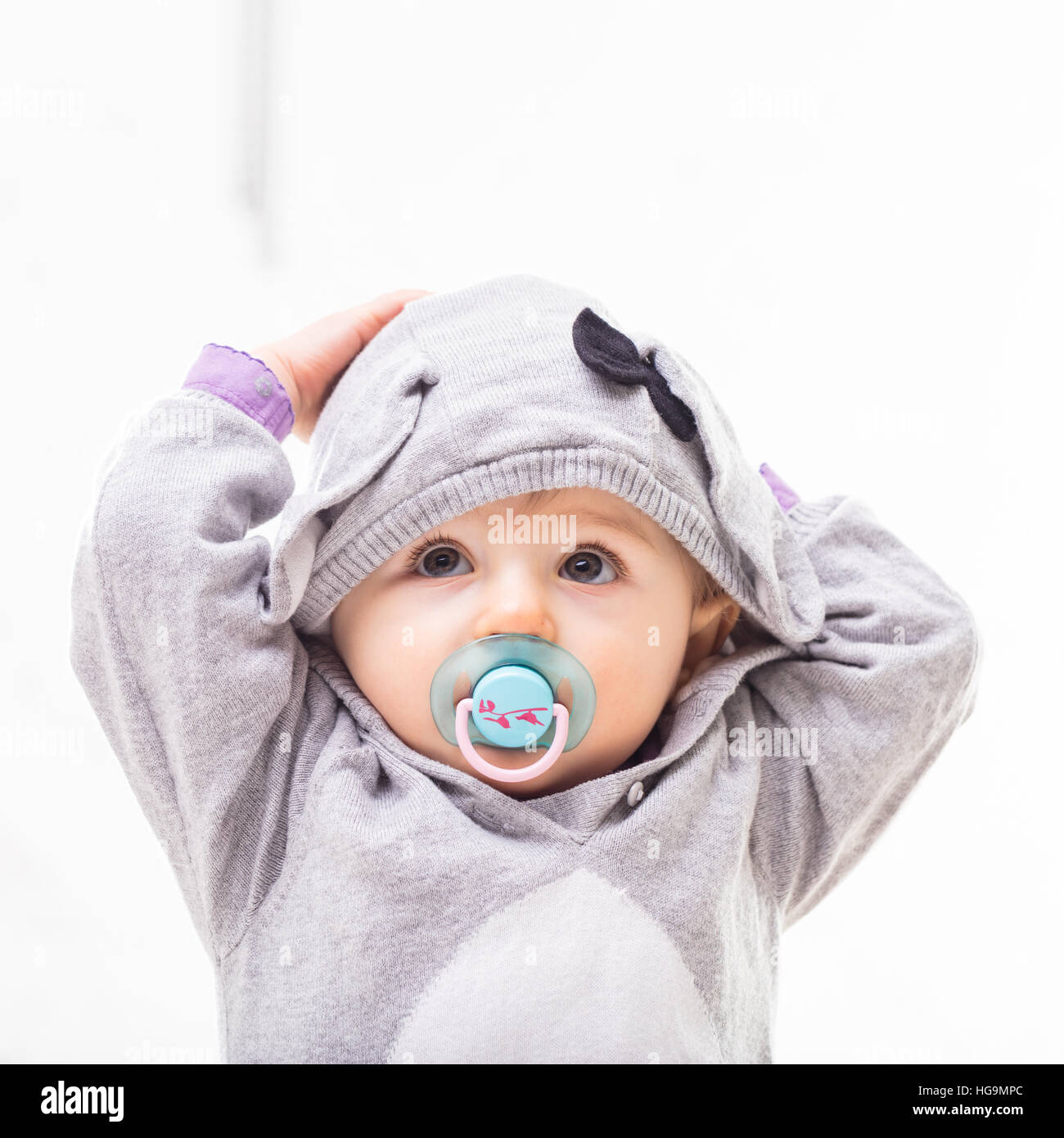 little infant girl touching her head with both hands as she looks for ...
