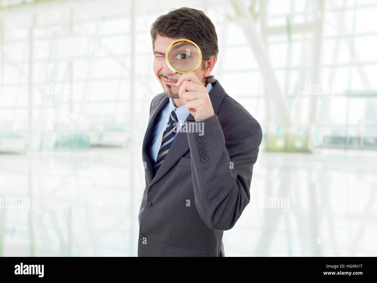 Isolated young business man with magnifying glass, at the office Stock ...