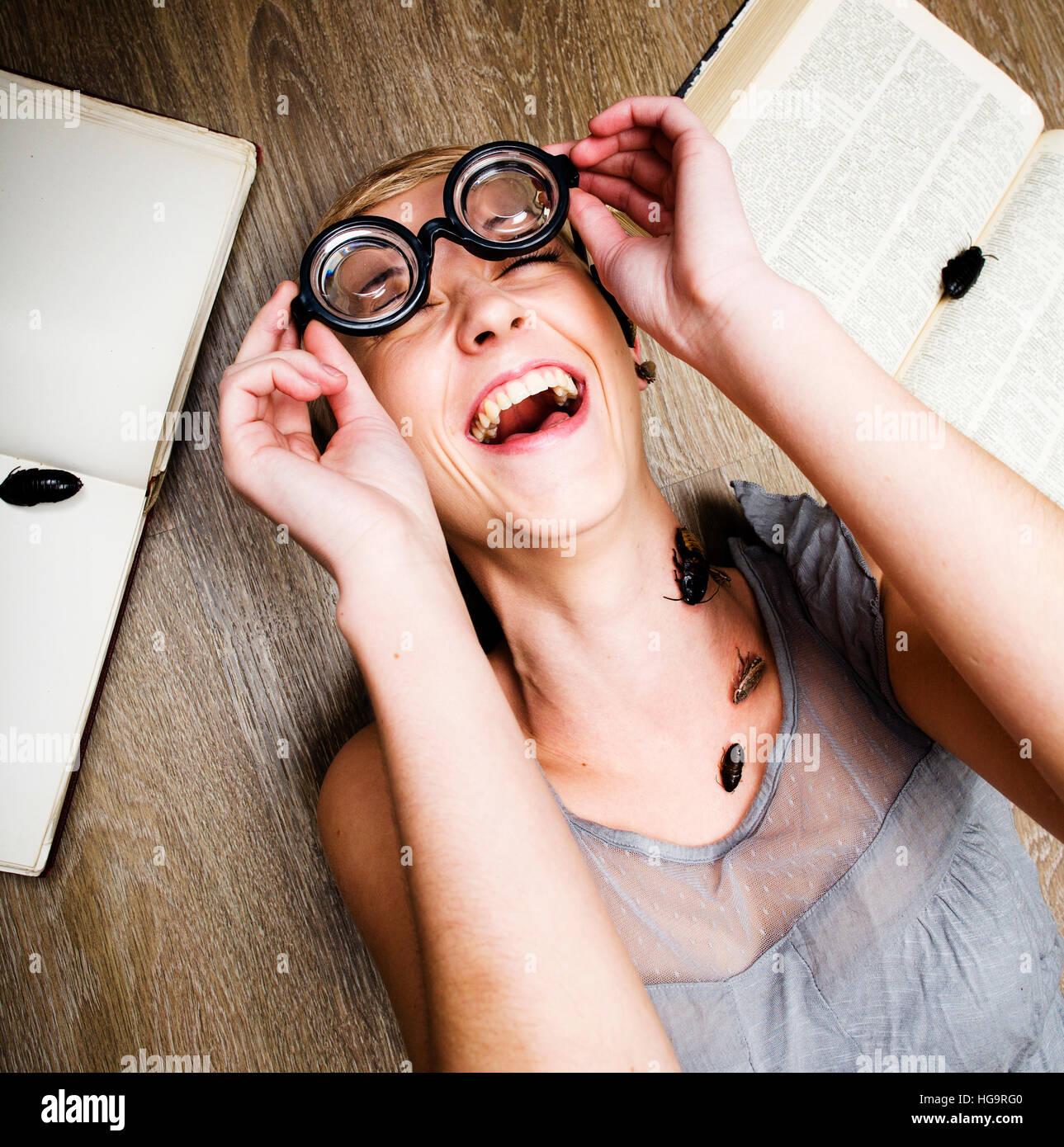 portrait of crazy student girl in glasses with books and cockroaches ...