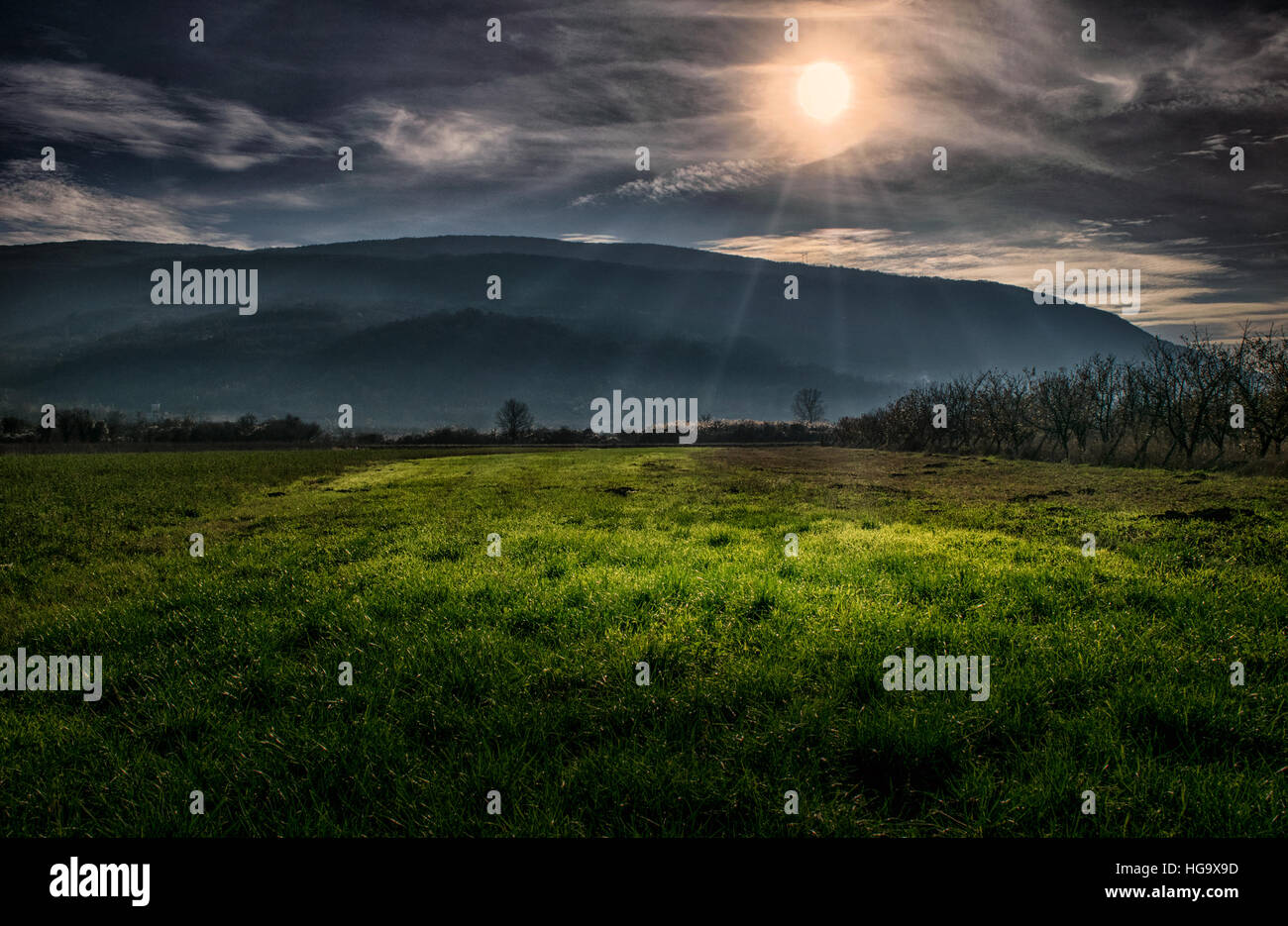 Evening sun rays on a meadow and hills landscape Stock Photo - Alamy