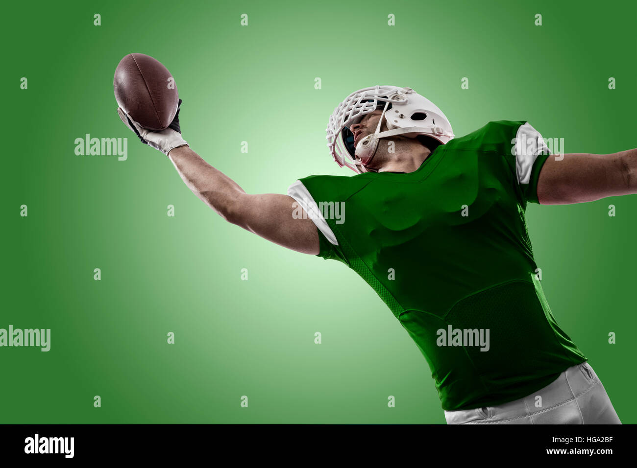Football Player with a green uniform making a catch on a green ...