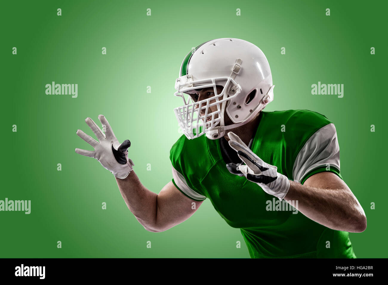 Football Player with a green uniform making a tackle on a green ...