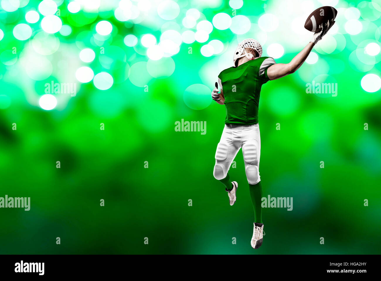 Football Player with a green uniform making a catch on a green lights ...