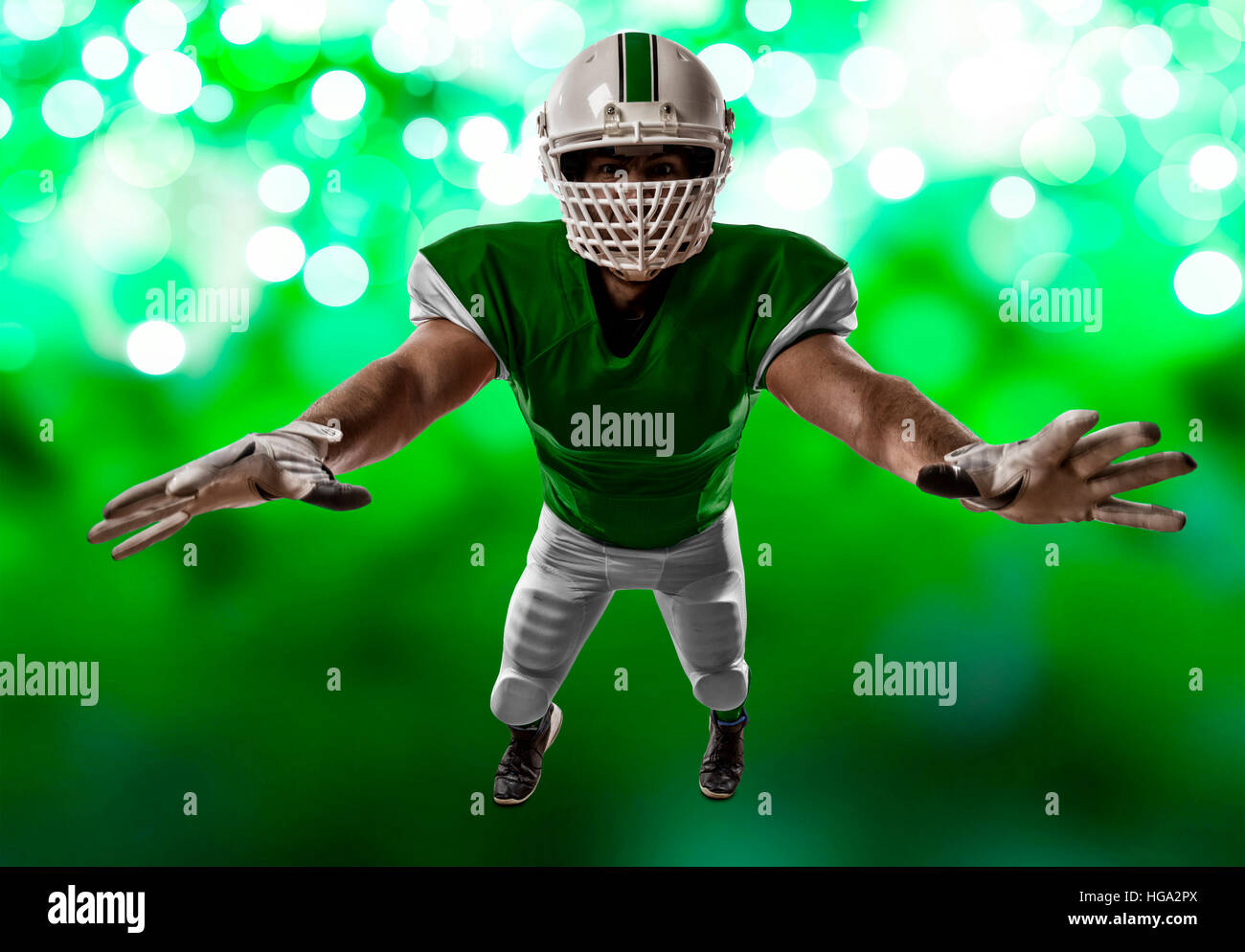 Football Player with a green uniform making a tackle on a green lights ...