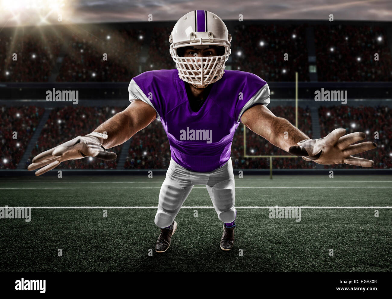 Football Player with a purple uniform making a tackle on a stadium ...
