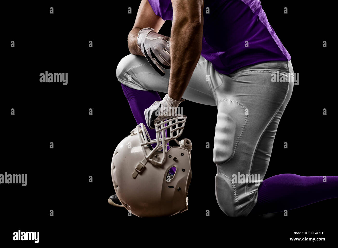 Football Player with a purple uniform on his knees, on a black ...