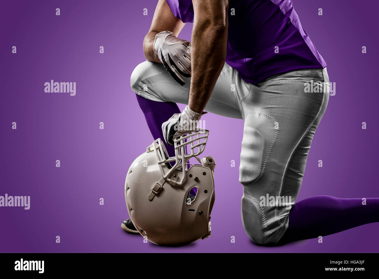 Football Player with a purple uniform on his knees, on a purple ...