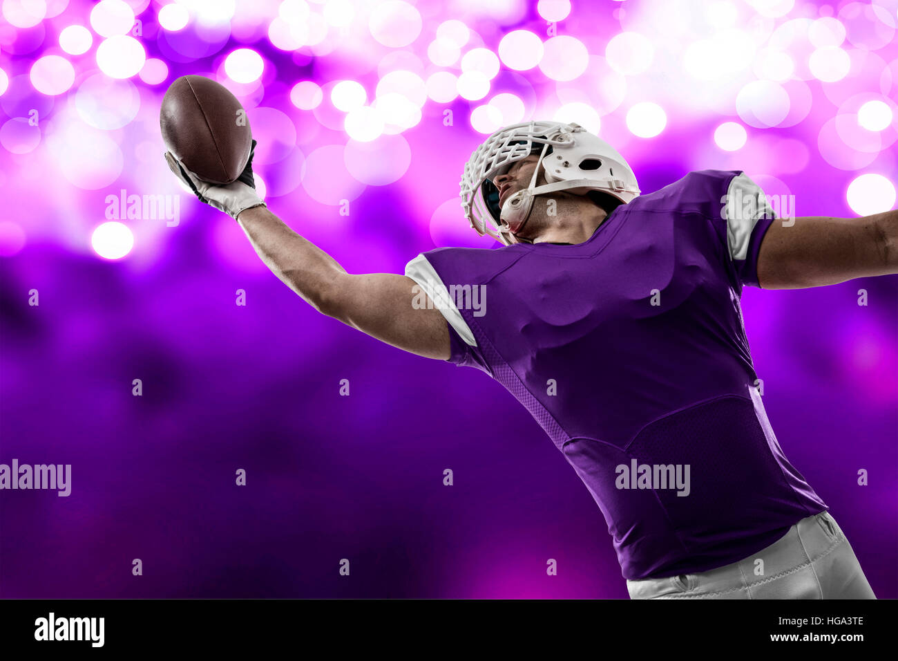 Football Player with a purple uniform making a catch on a purple lights ...