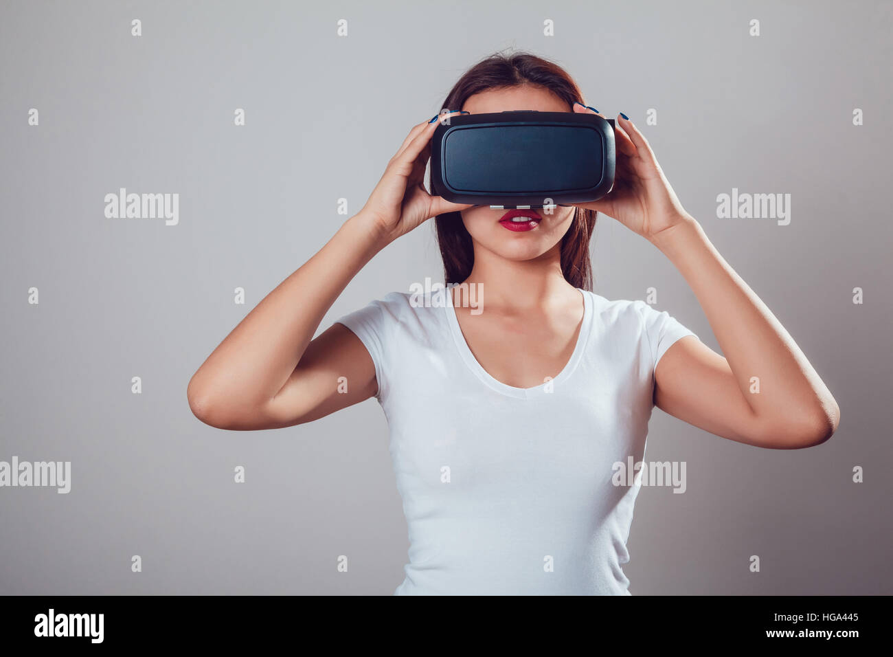 Attractive woman wearing virtual reality goggles. VR headset. Virtual reality concept on grey ...