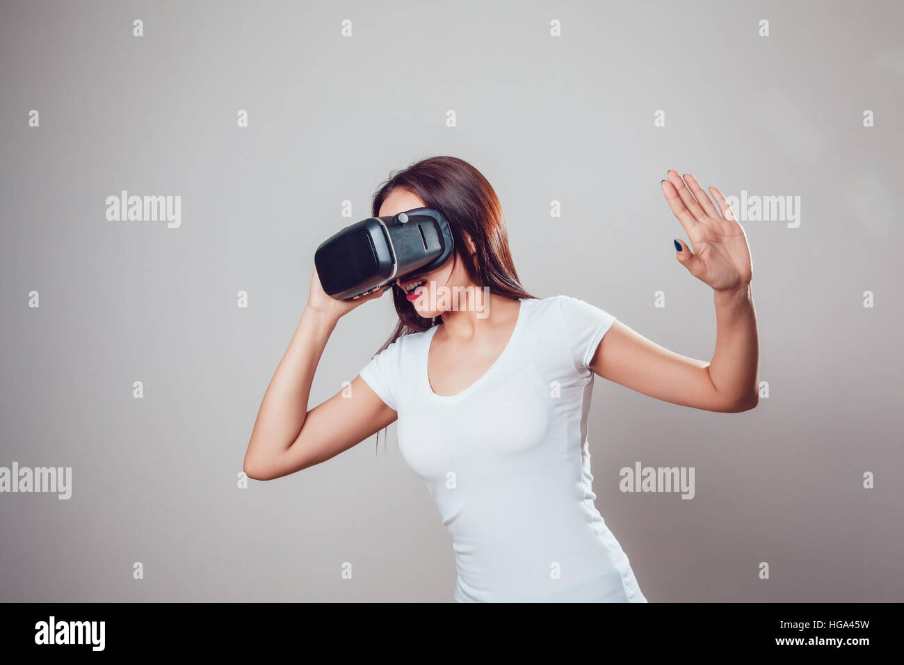 Attractive woman using virtual reality goggles on grey background. VR headset Stock Photo - Alamy