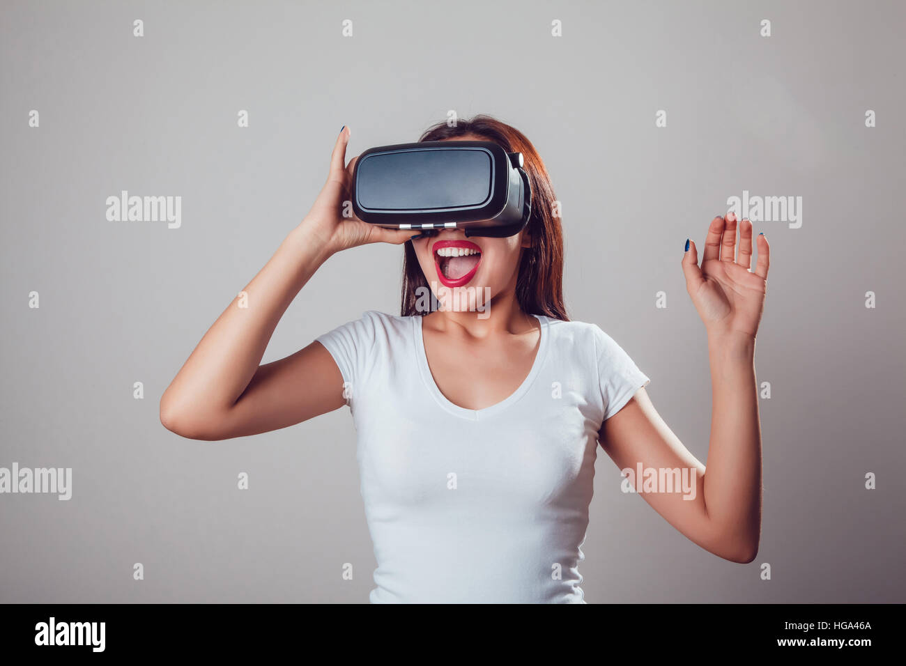 Attractive woman wearing virtual reality goggles. VR headset. Virtual reality concept on grey ...