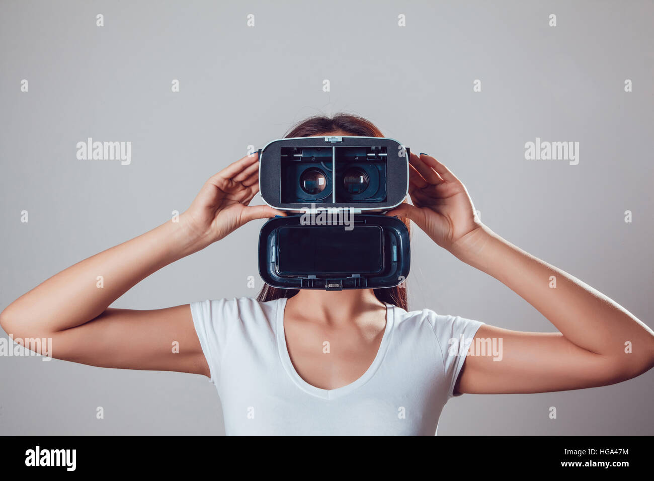 Attractive woman wearing virtual reality goggles. VR headset. Virtual reality concept on grey ...