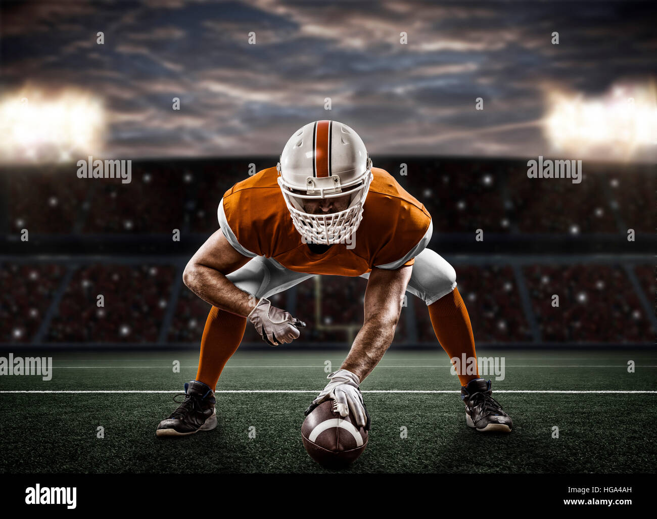 Football Player with a orange uniform on the scrimmage line, on a ...