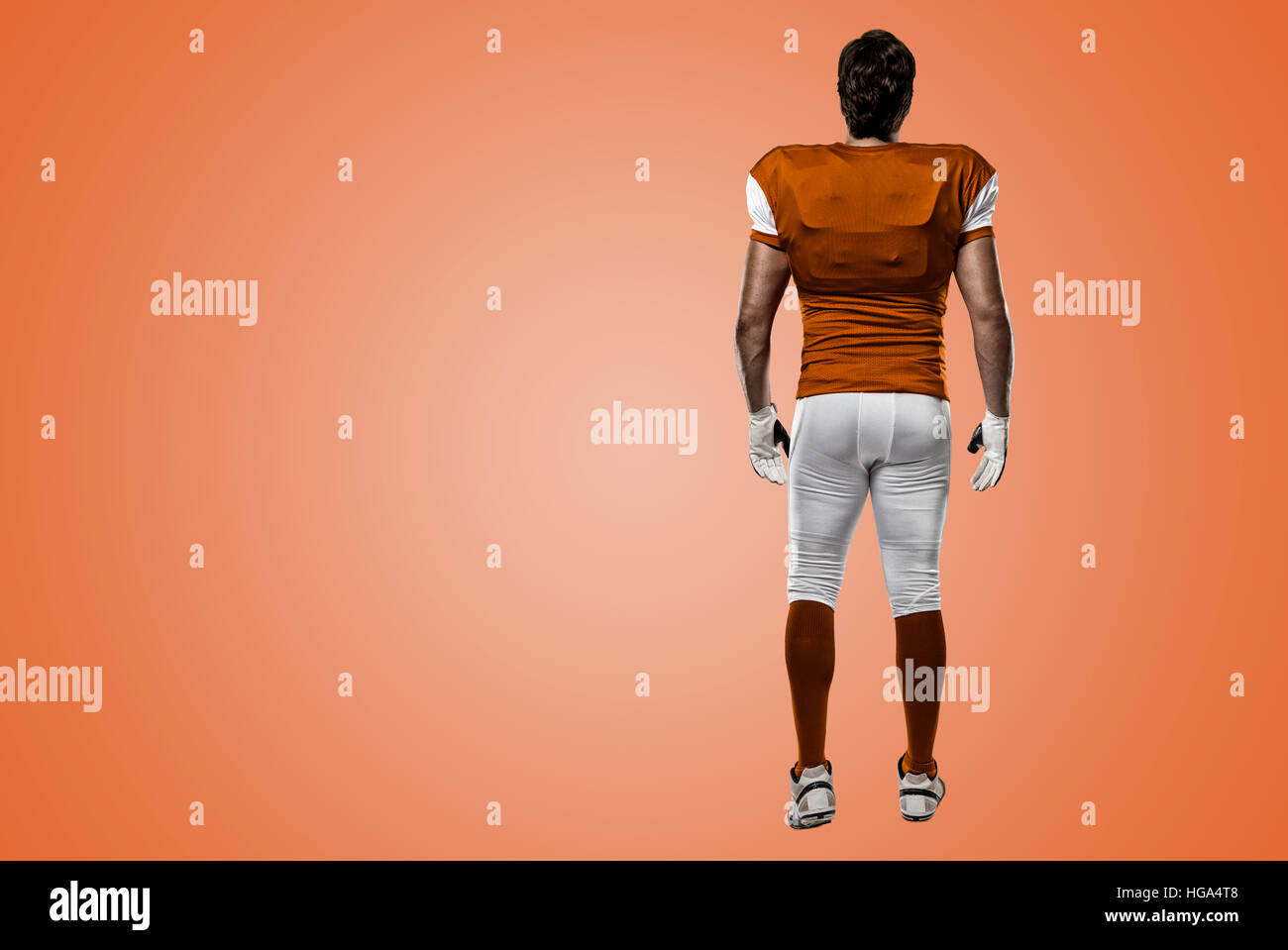 Football Player with a orange uniform walking, showing his back on a ...