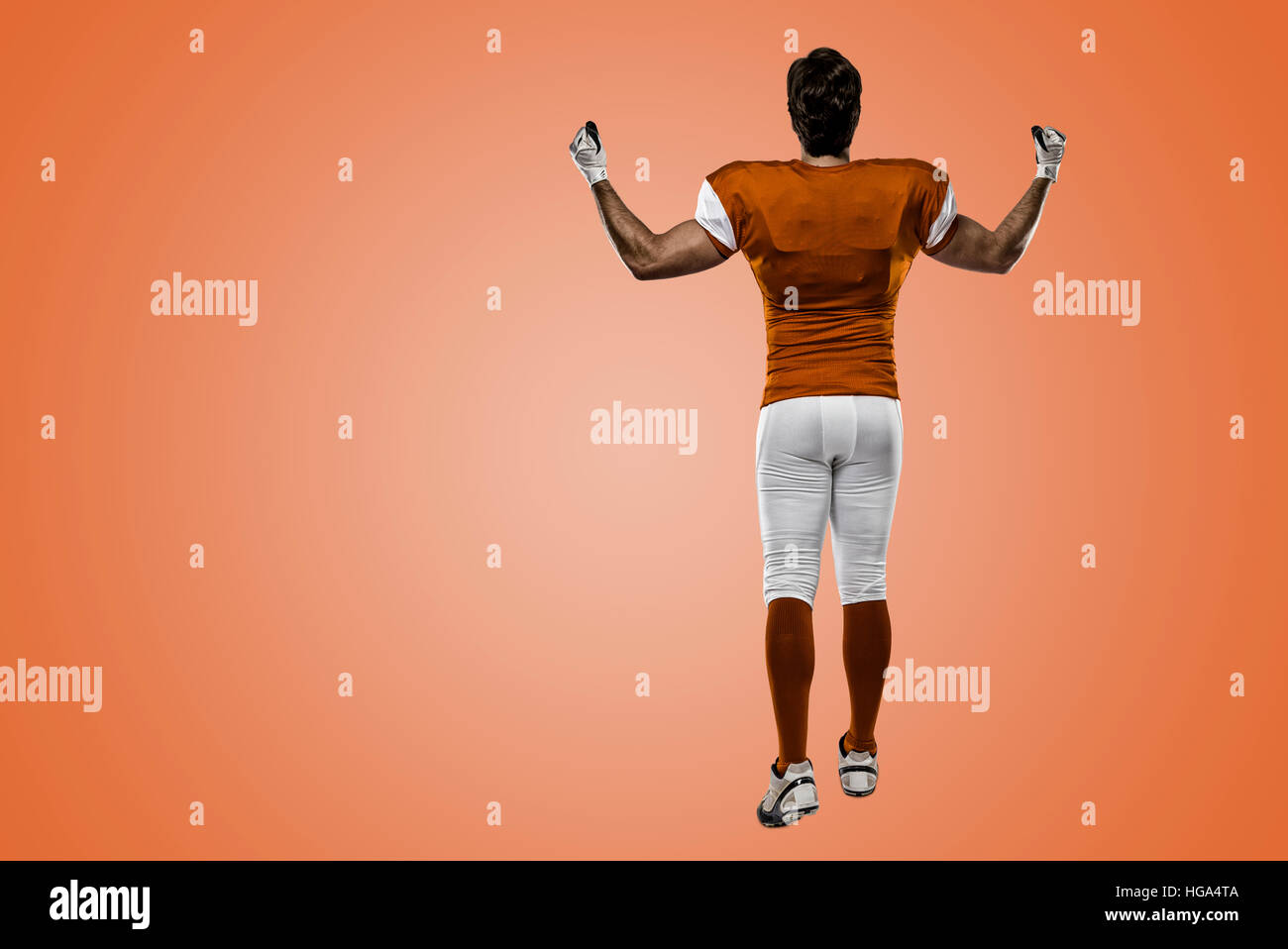 Football Player with a orange uniform walking, showing his back on a ...