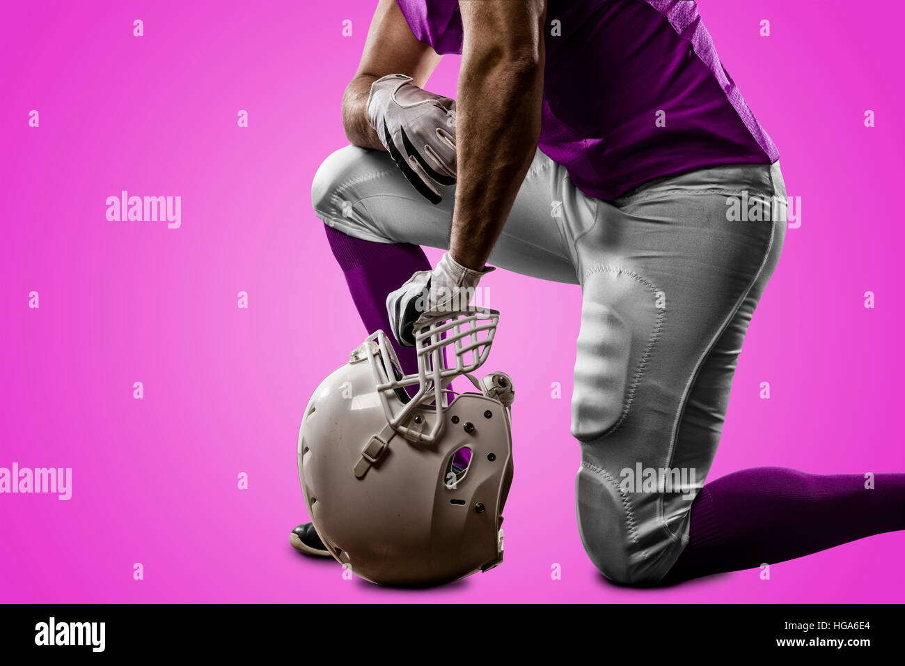 Football Player with a pink uniform on his knees, on a pink background ...