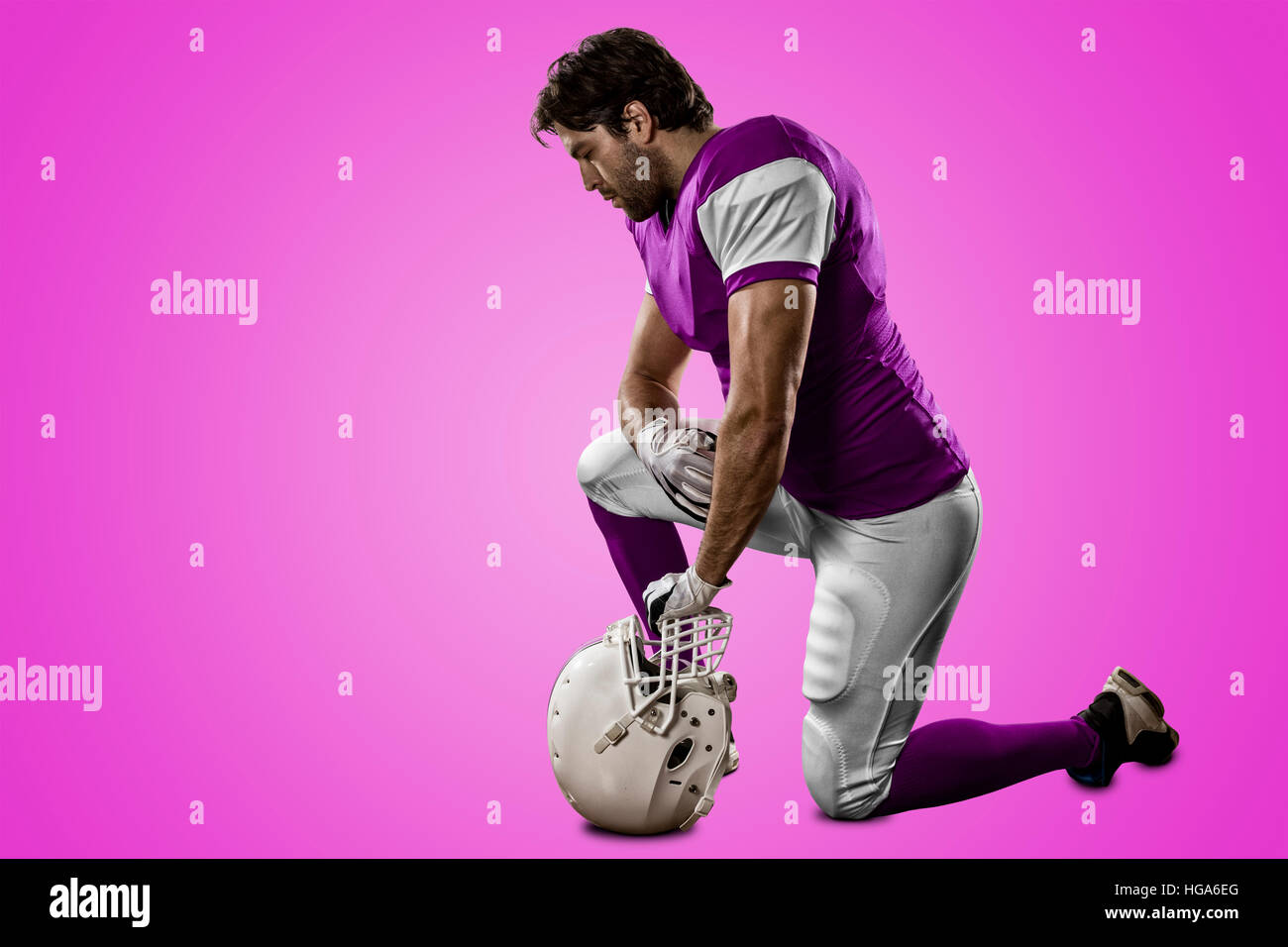 Football Player with a pink uniform on his knees, on a pink background ...