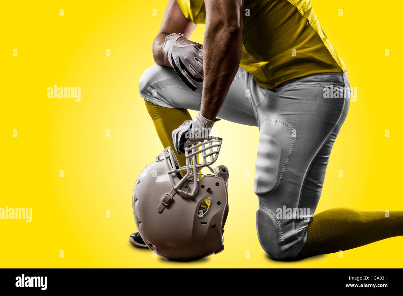 Football Player with a yellow uniform on his knees, on a yellow ...