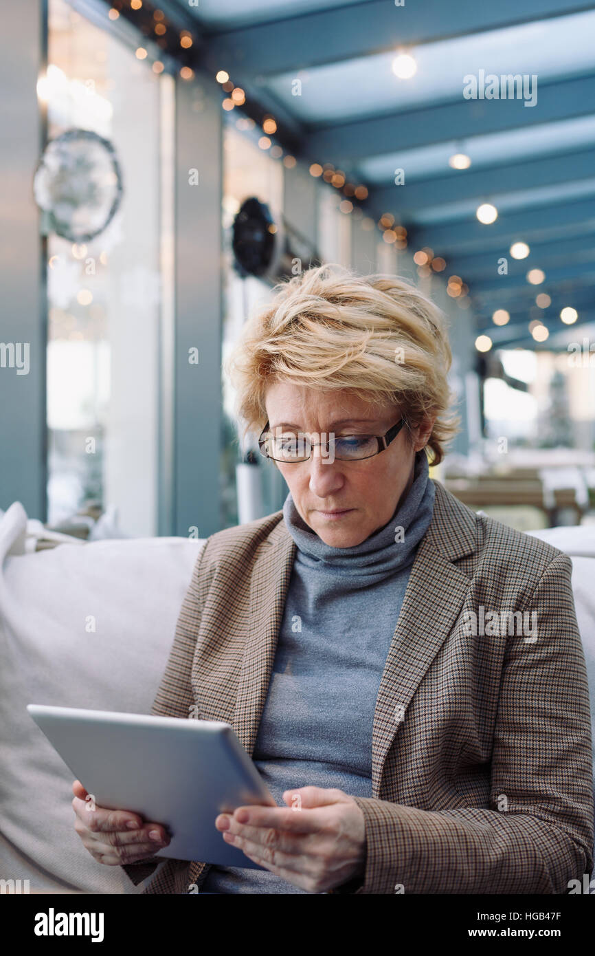 Mid age woman with tablet sitting cafe Stock Photo - Alamy