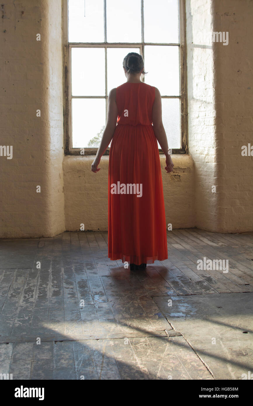 Rear view of a woman standing by the window Stock Photo - Alamy