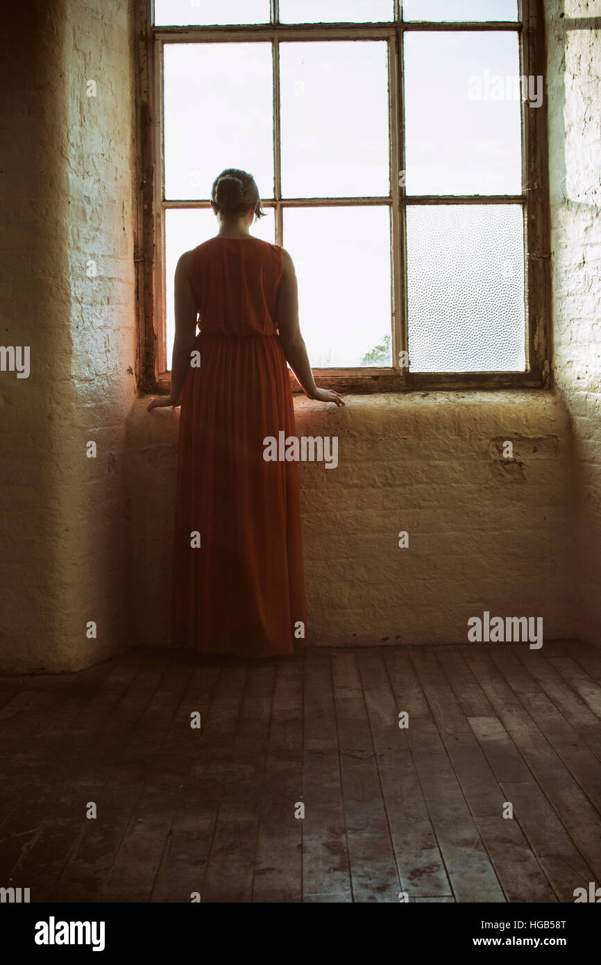 Rear view of a woman standing by the window Stock Photo - Alamy