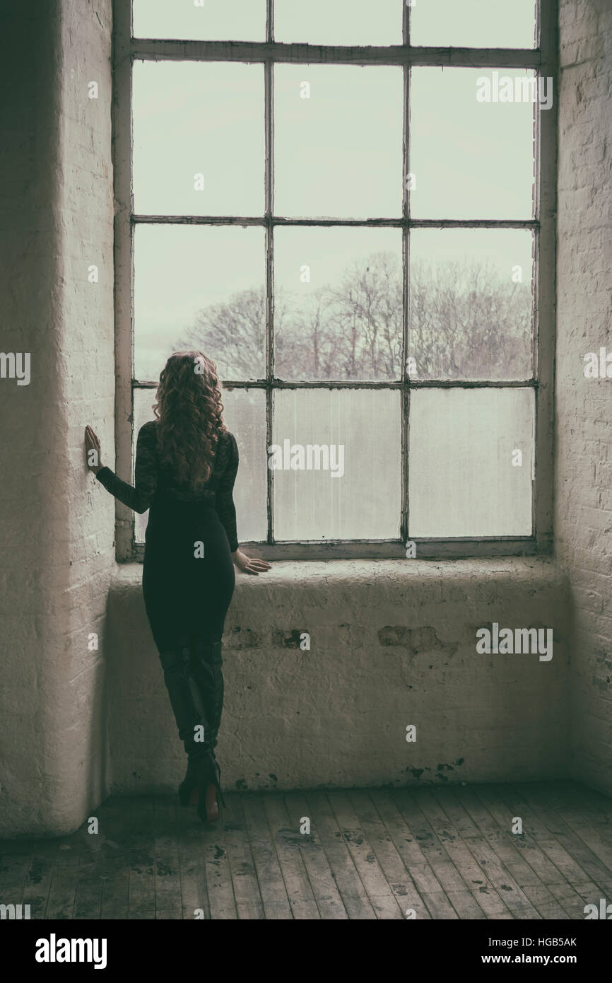 Rear view of a woman looking out of the window Stock Photo - Alamy