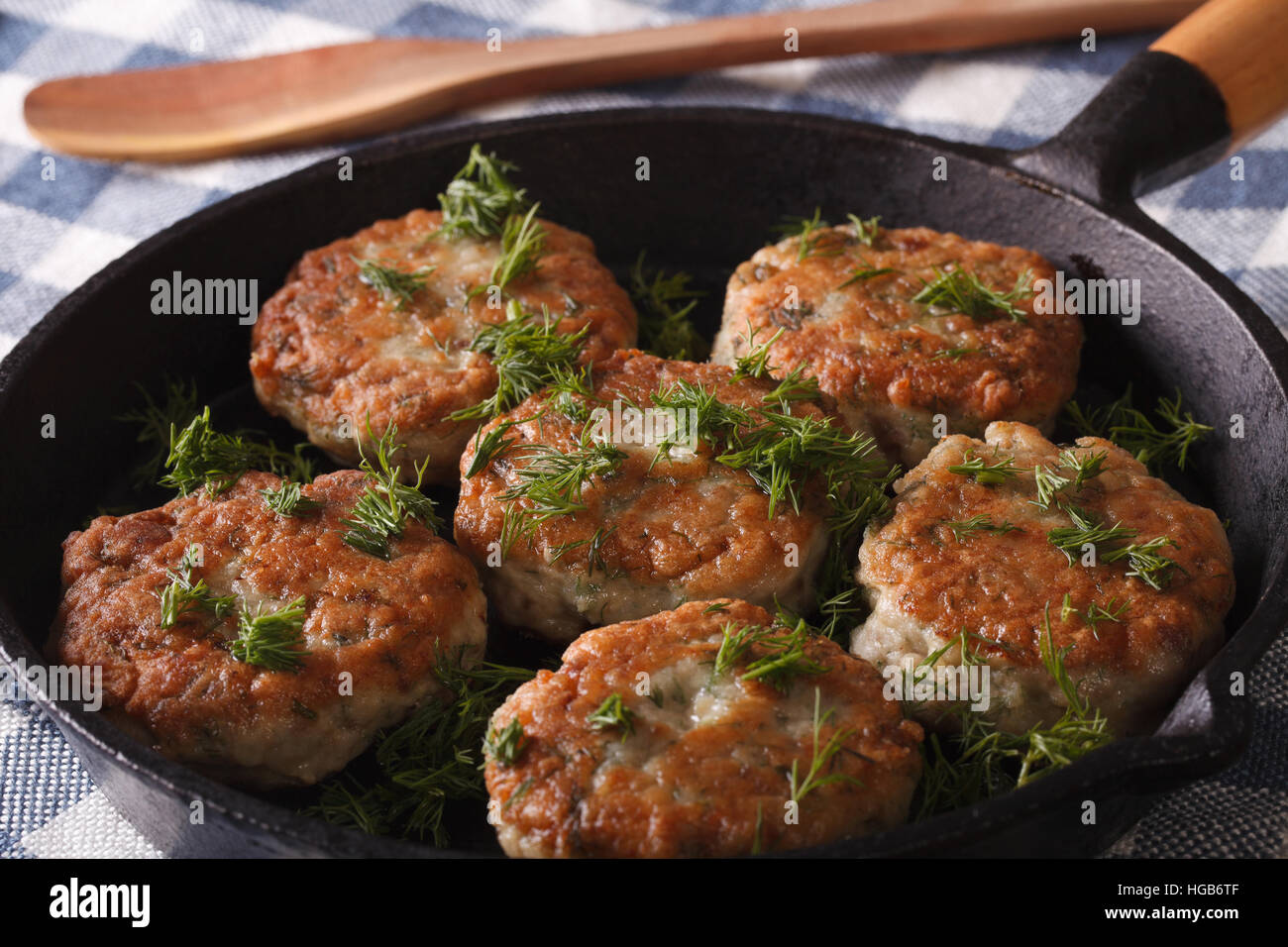 Cooking fish cakes with herbs close-up in a frying pan. Horizontal ...