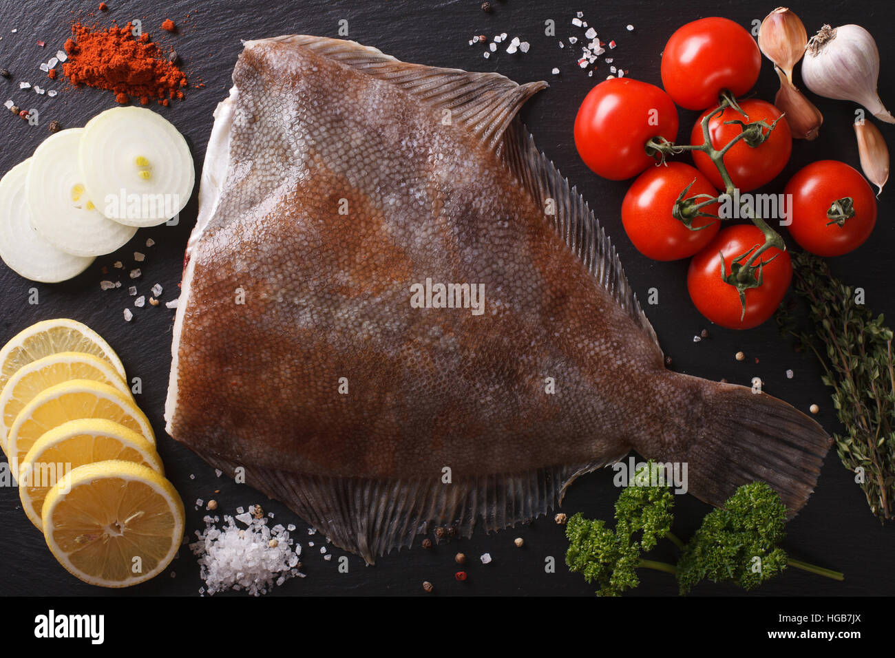 Fresh raw flounder with ingredients on a slate board closeup ...