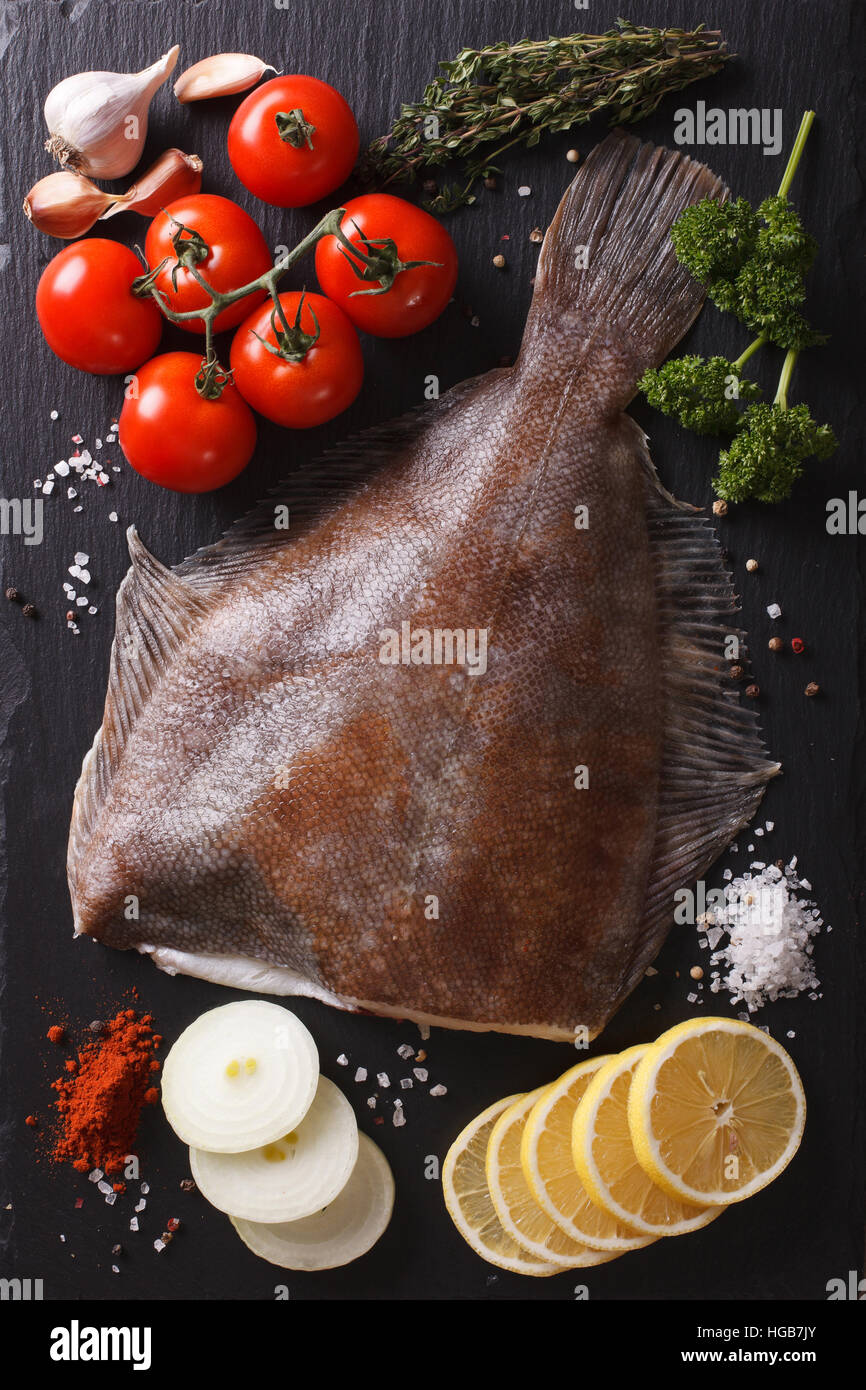 Fresh raw flounder with ingredients on a black board closeup. vertical ...