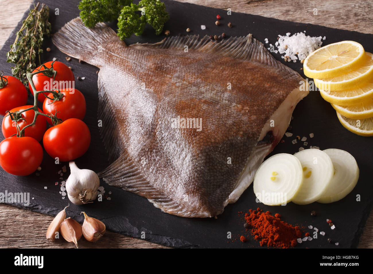 raw flounder with ingredients on a slate board on a table closeup ...