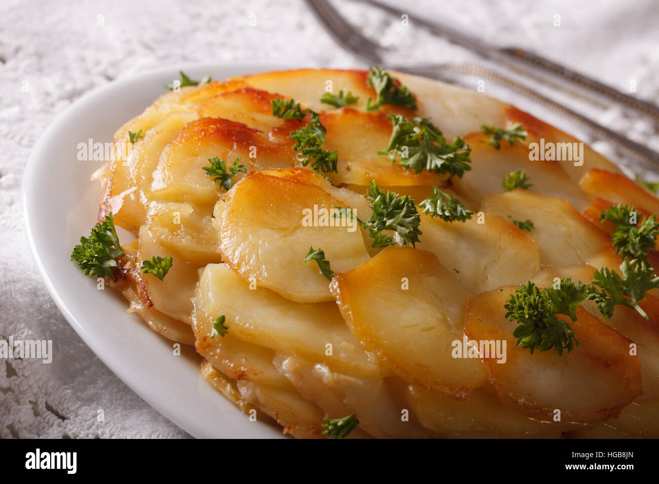 Anna potatoes with butter on a white plate macro. horizontal Stock ...