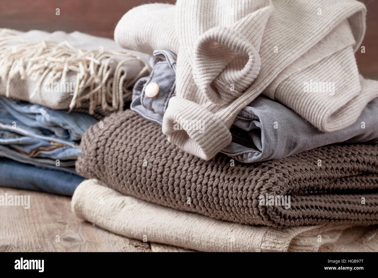 stack of of warm clothes, stack of jeans on the old wooden background ...