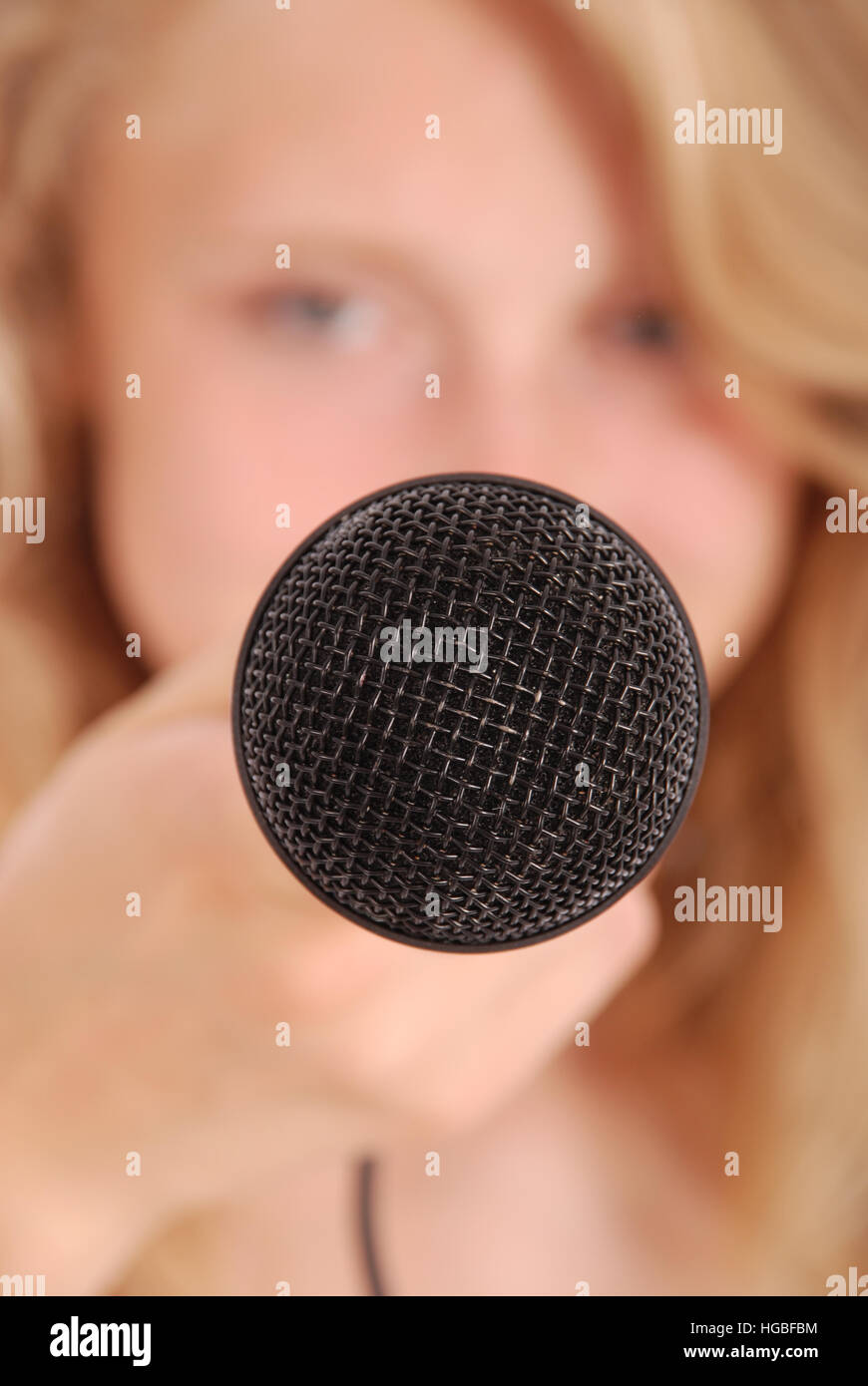 Teenage girl holding a microphone in front. Focus on the microphone ...
