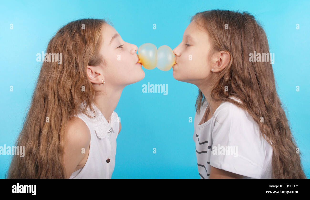 Two young girls playing with chewing gum isolated on blue Stock Photo ...