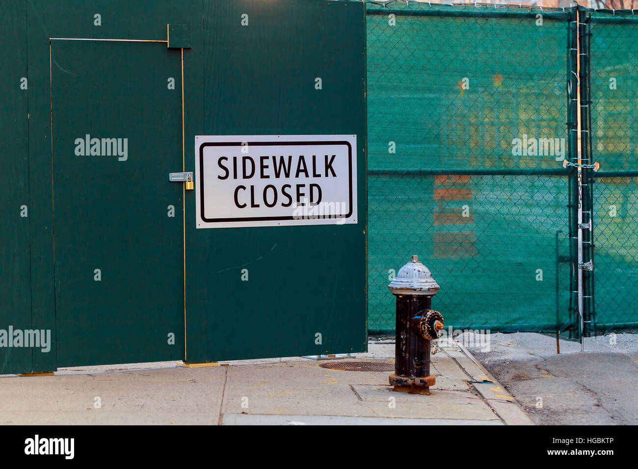 SIDEWALK CLOSED sign posted on green construction wall barrier ...