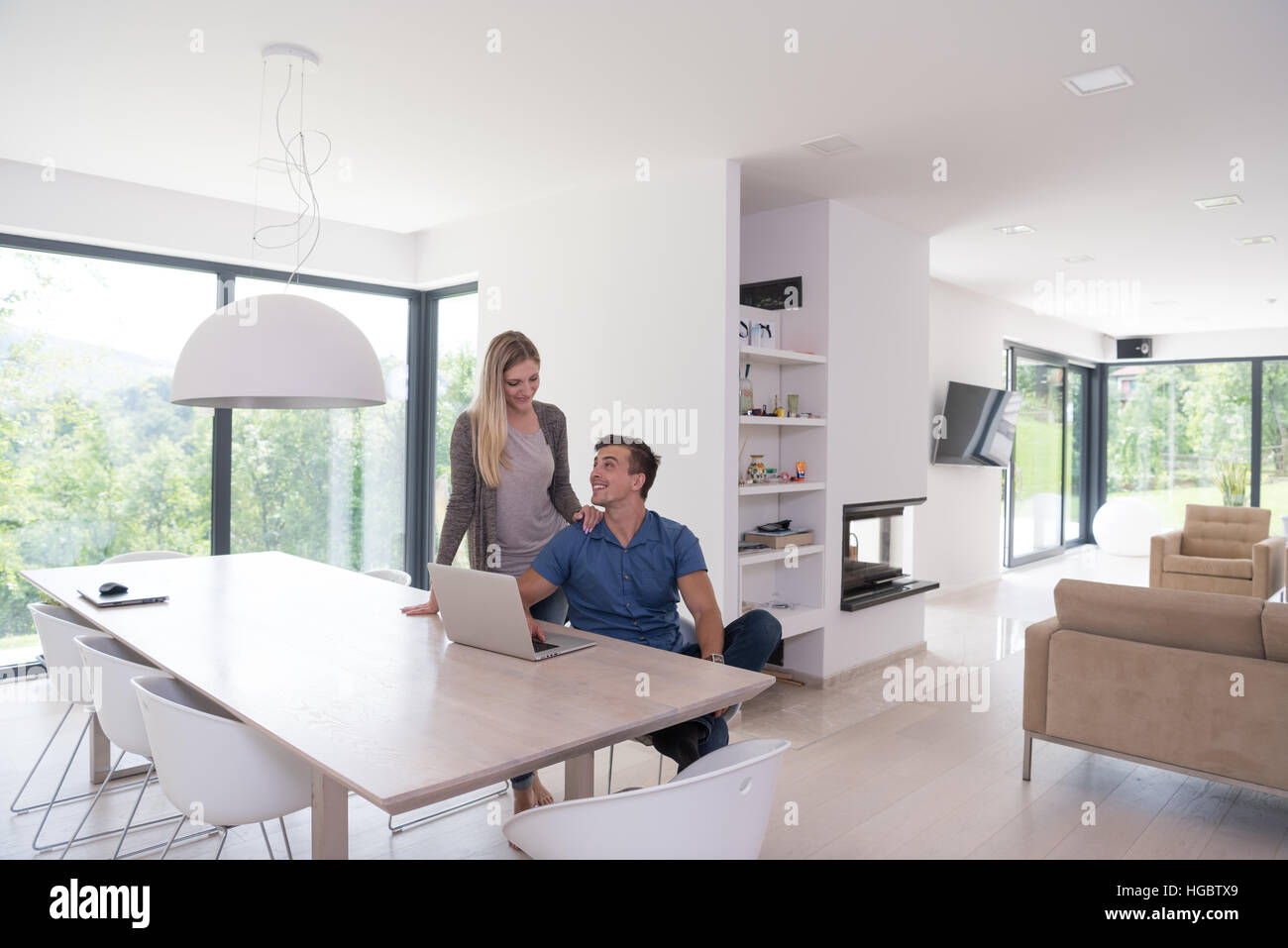 Young couple using laptop computer at luxury home together, looking at ...