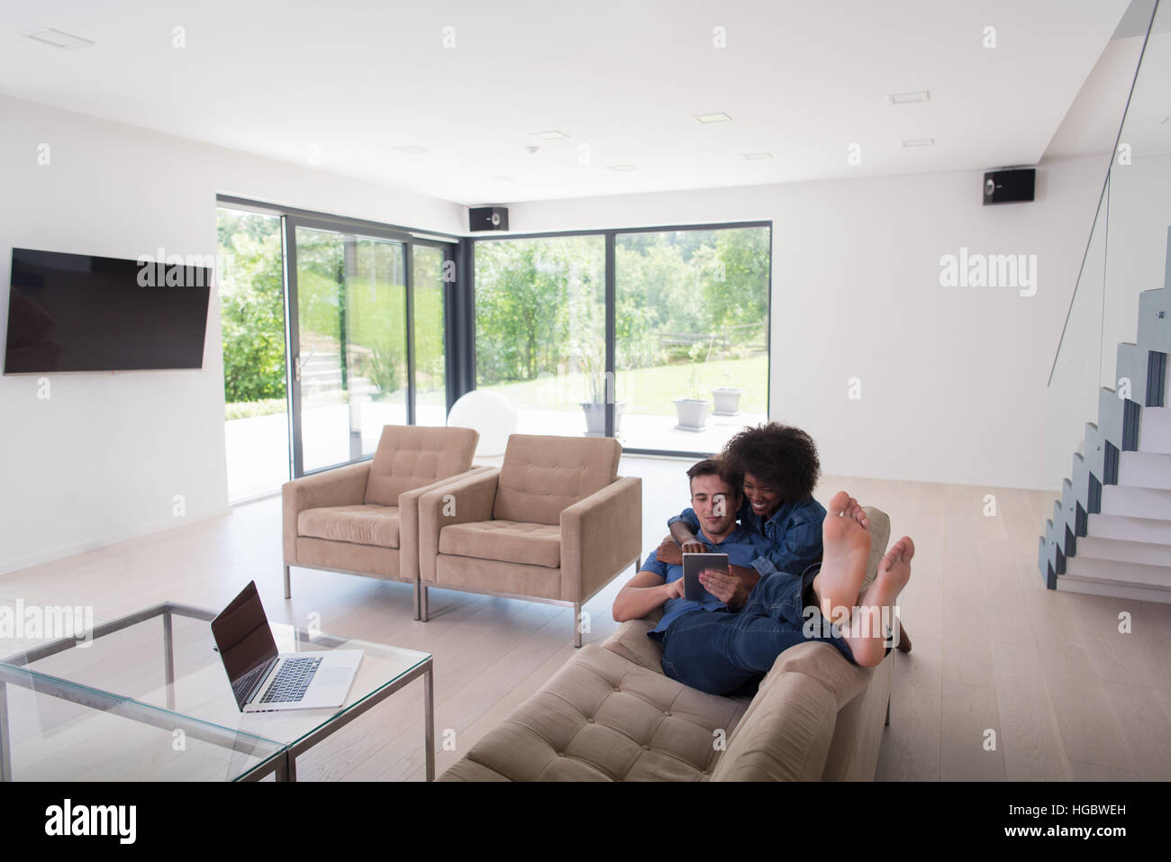 Young multiethnic couple relaxes in the luxury living room, using a ...
