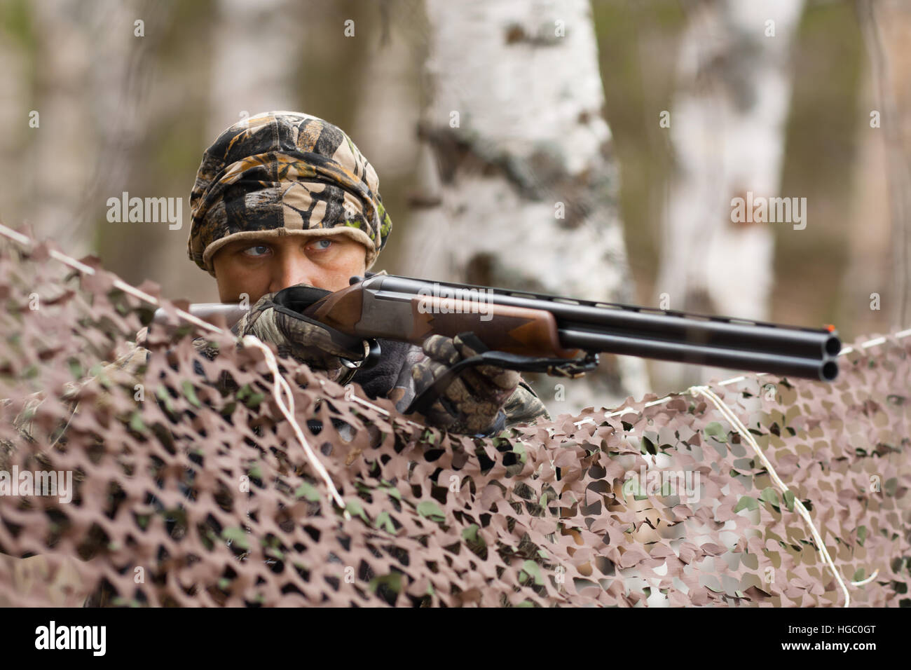 hunter aiming from behind camouflage netting Stock Photo - Alamy