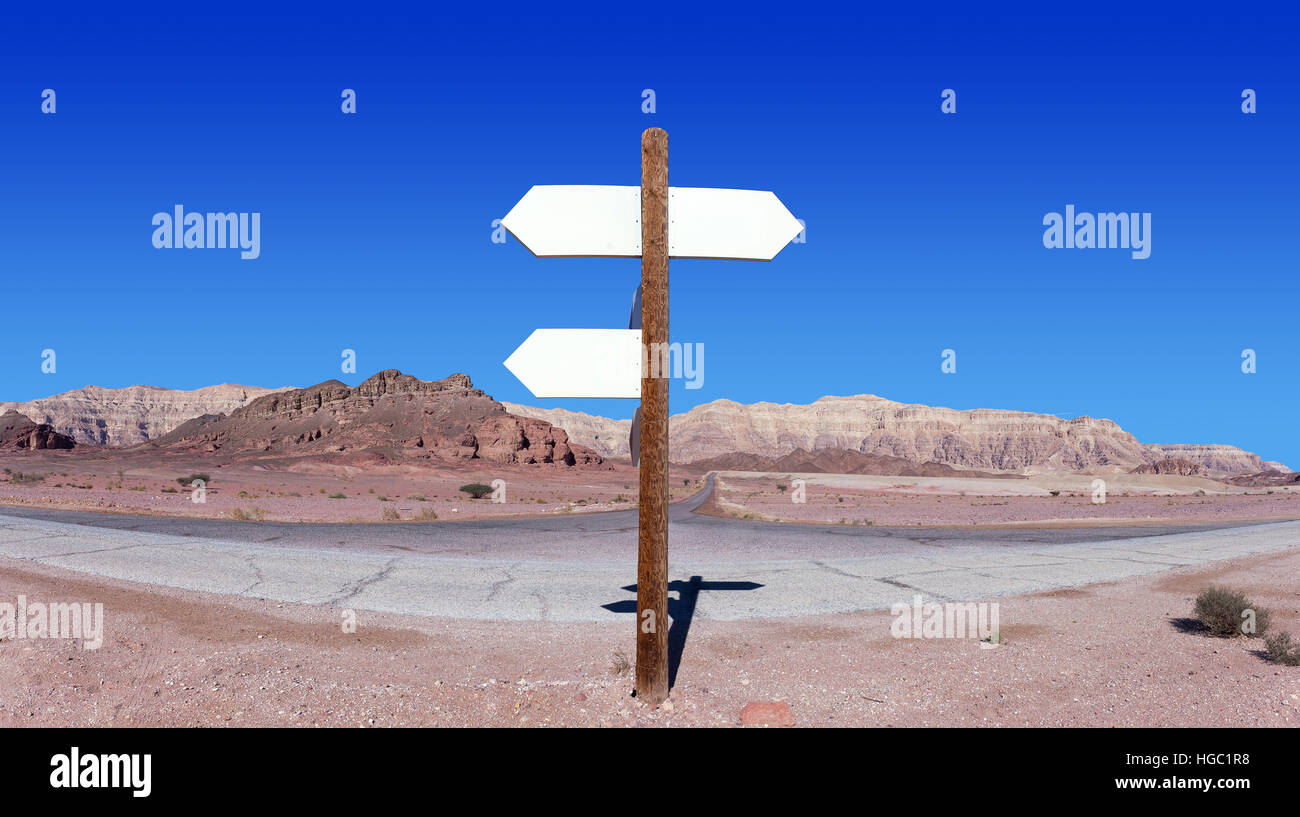 Empty arrow shaped signs in the middle of the desert with blue sky and ...