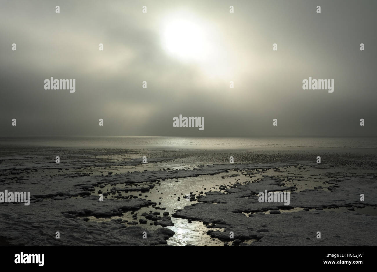 Irregular margin sea ice on sand beach towards calm receding seawater ...