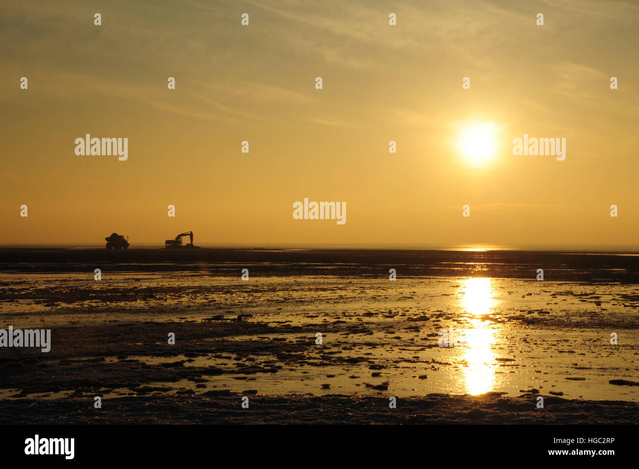 Sea ice sand expanse towards sand-winning vehicles and white sun ...