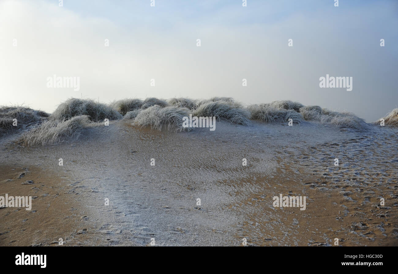 Blue sky white clouds view landward side of sand dune with frost and ...