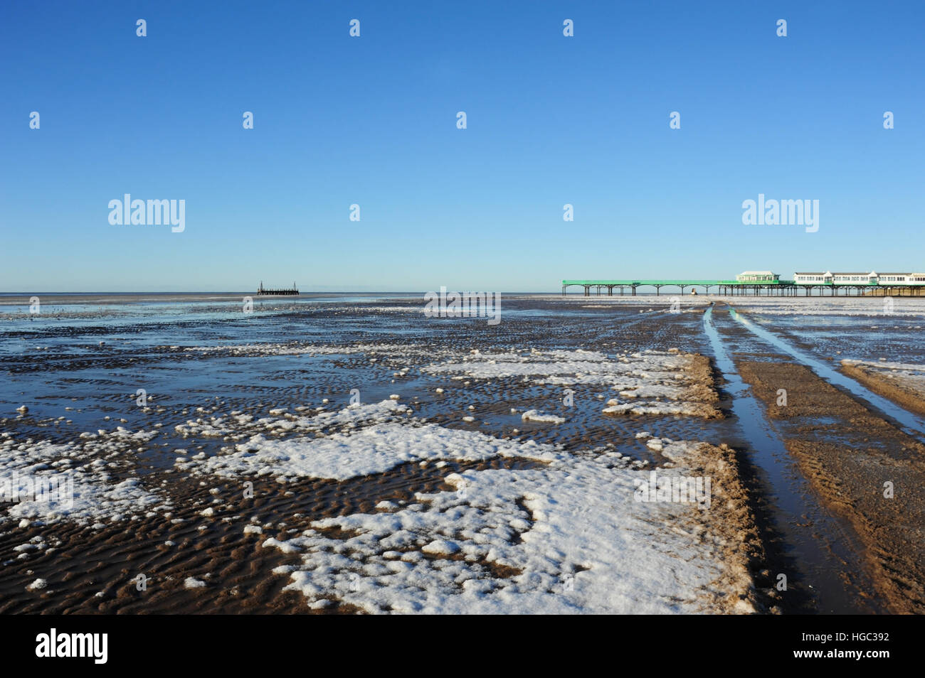 Blue sky view sand beach with land-fast sea ice and tractor tracks ...