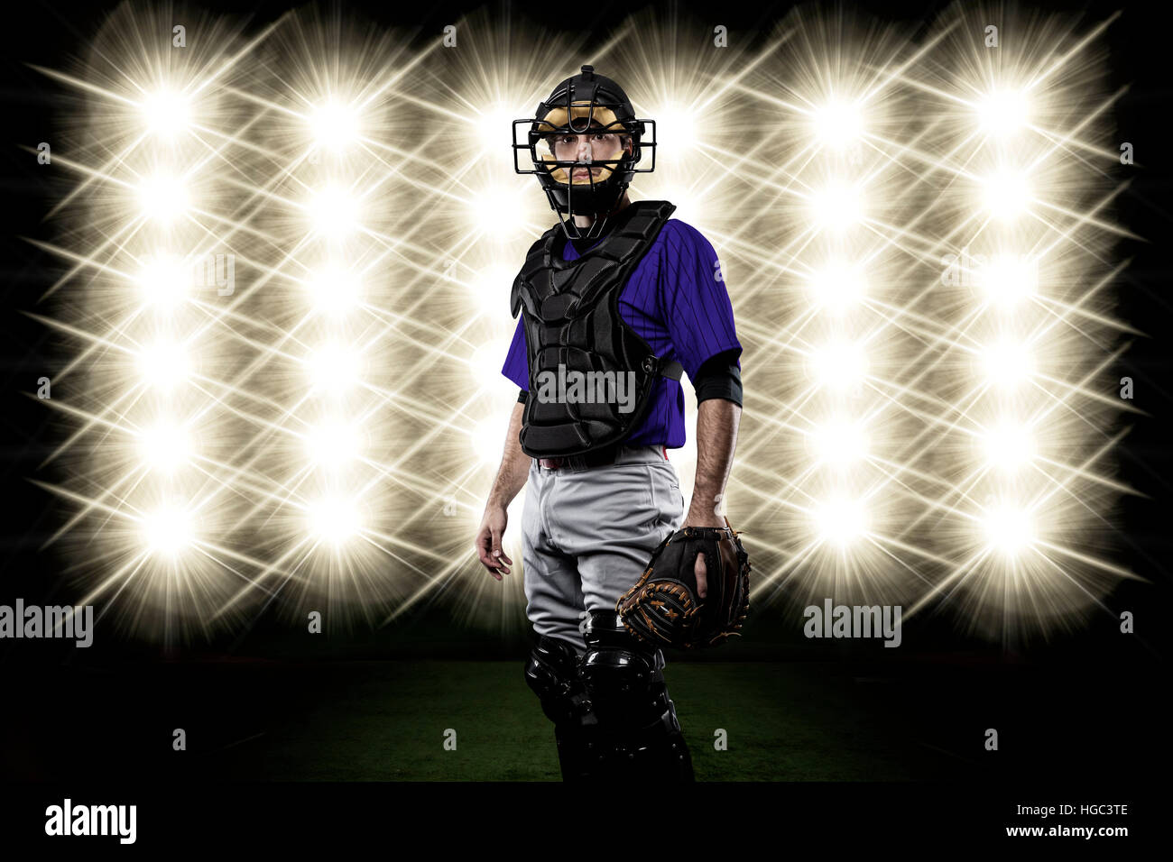 Catcher Player with a blue uniform in front of lights Stock Photo - Alamy